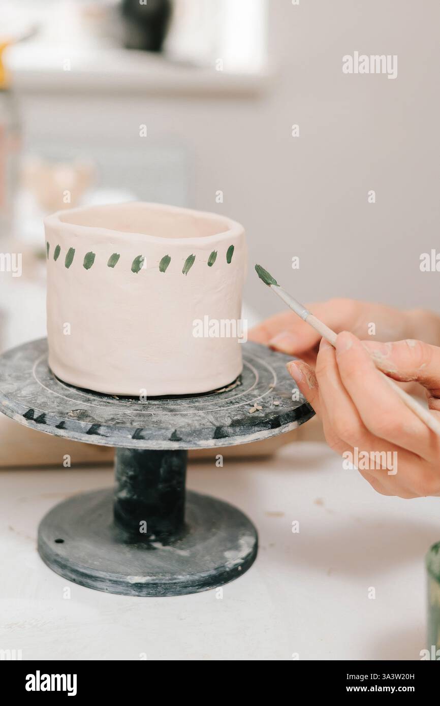 Artisan stamps decorative symbols on the dry clay of the cup. Process ...