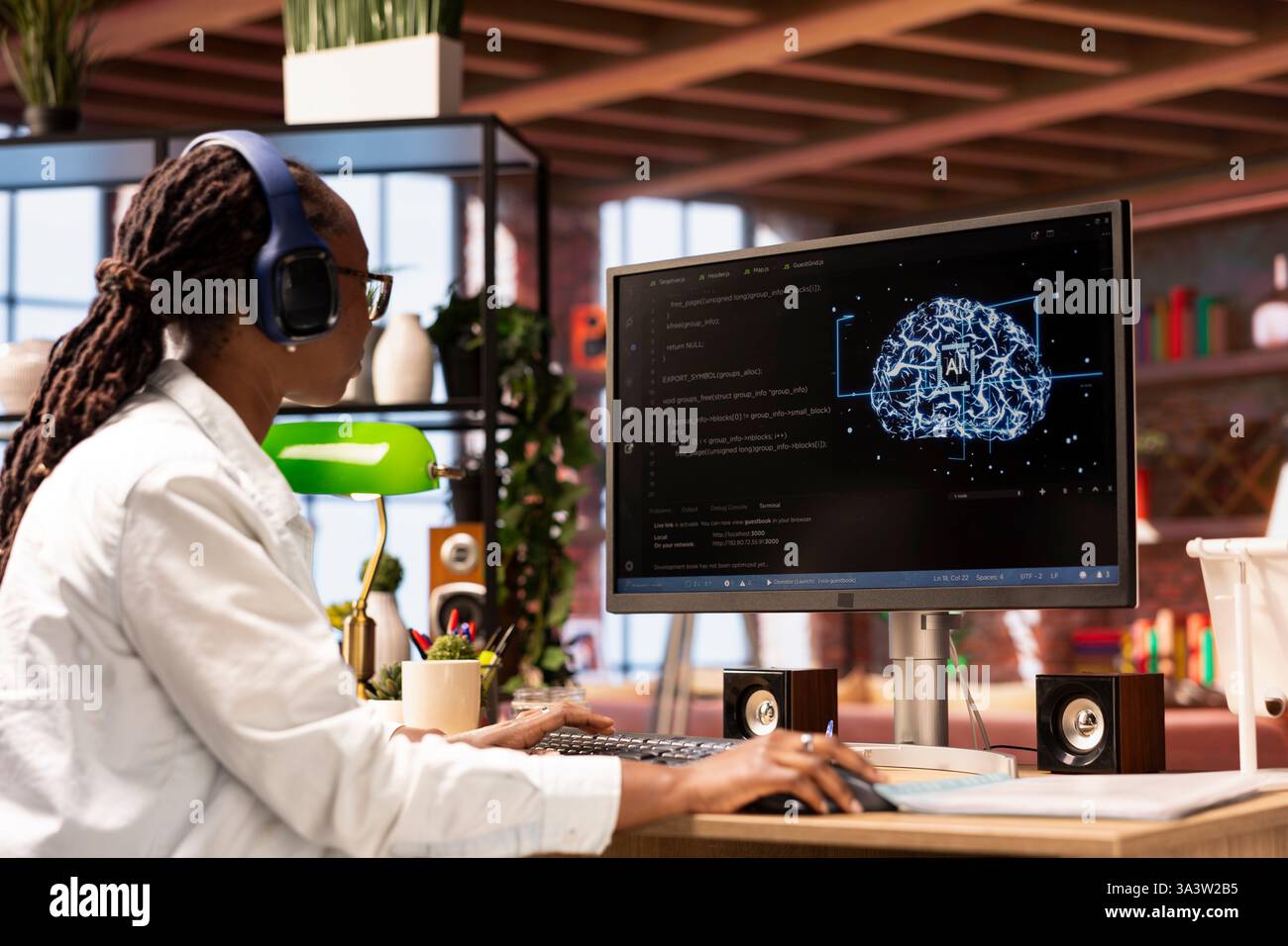 Programmer wearing headphones using computer at home for artificial intelligence computing ...