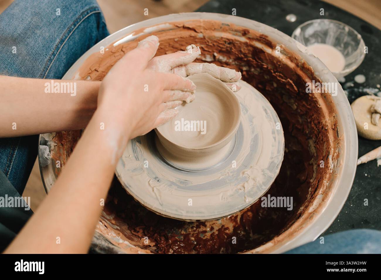 Artisan sculpts a pottery plate on the spinning wheel. Craftswoman is ...