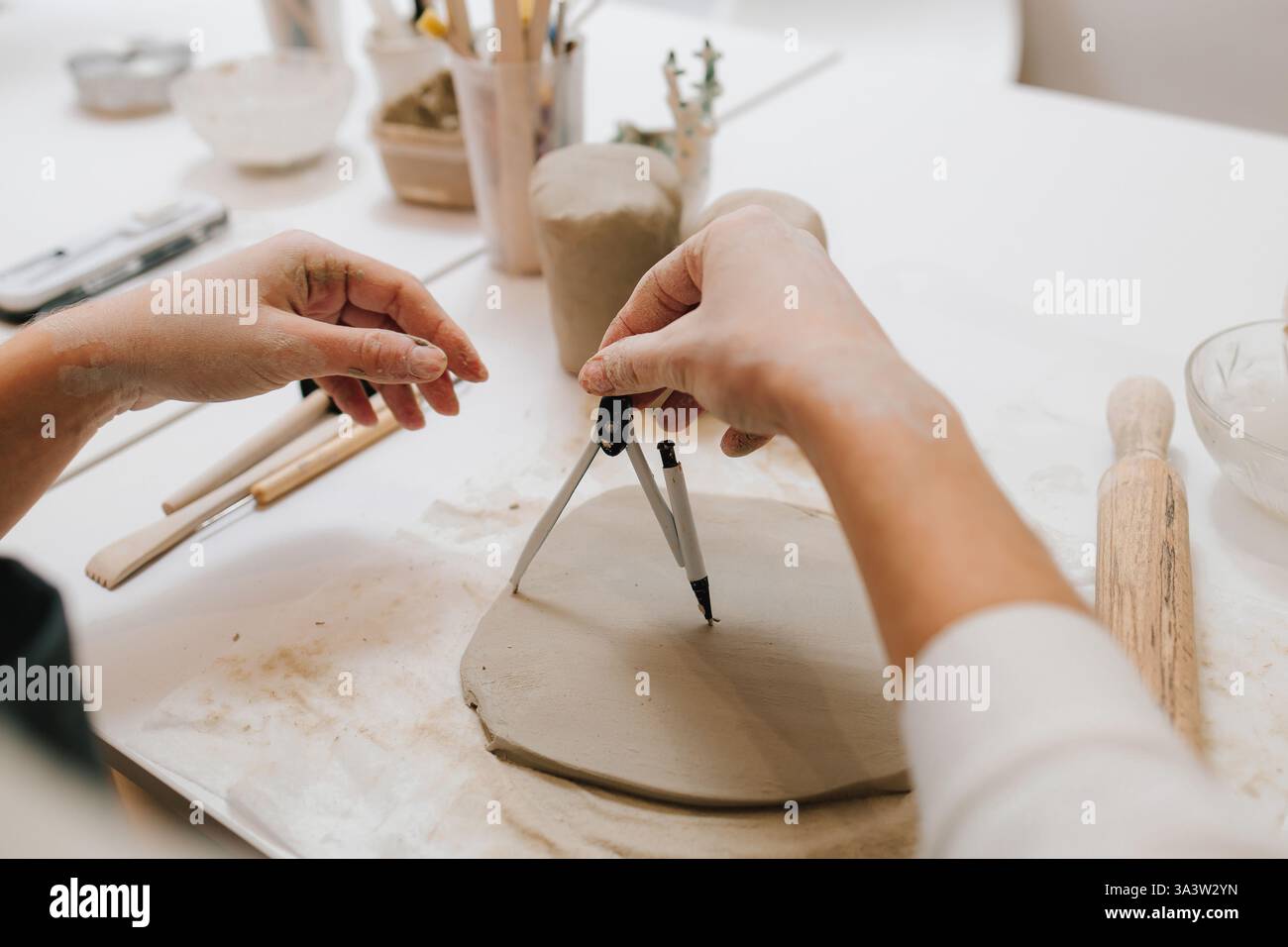 Artisan with compass shapes and refines a ceramic piece with precision ...