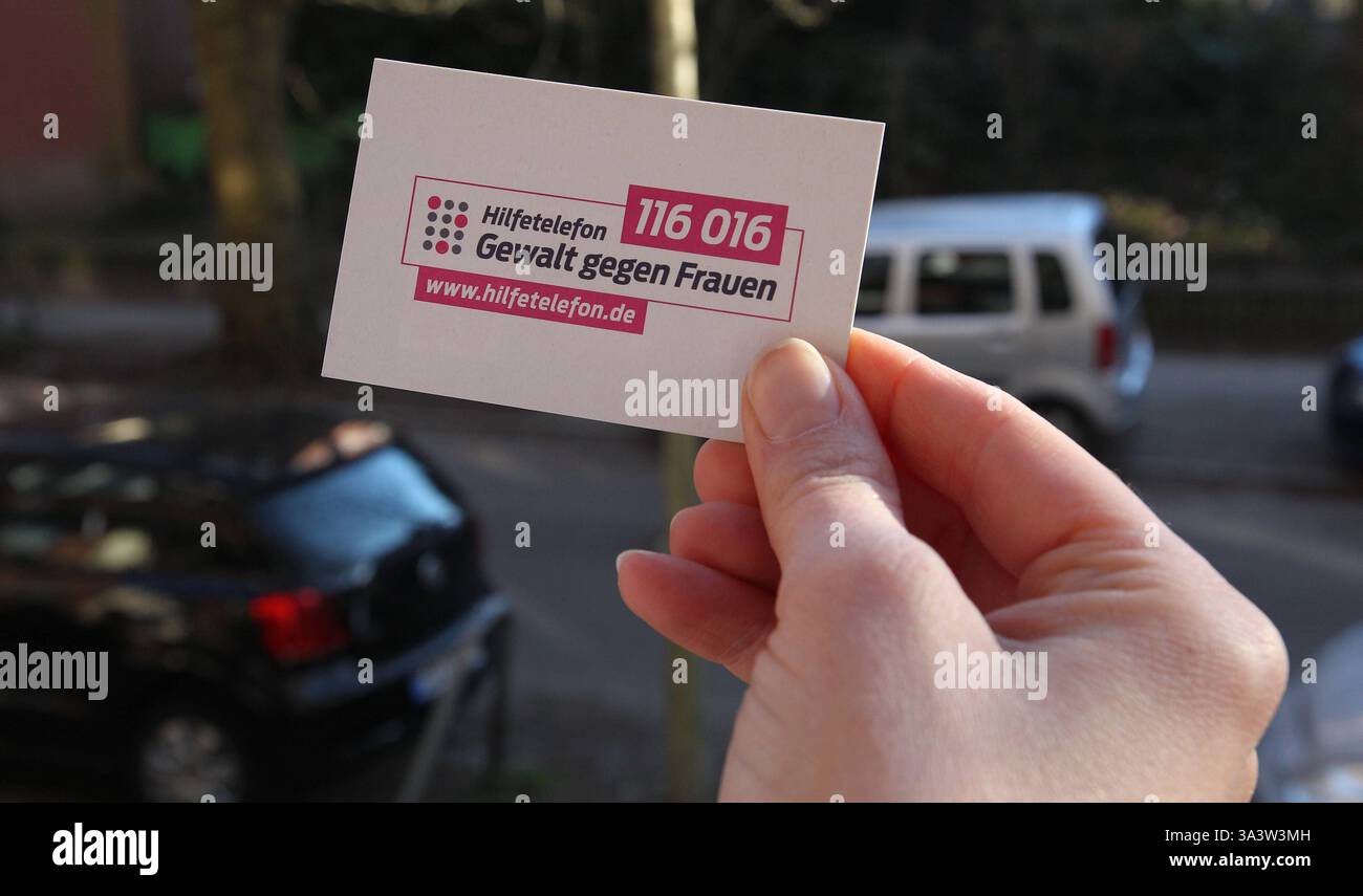 Eine Frau hält eine Karte vom Beratungsangebot Das Hilfetelefon Gewalt ...