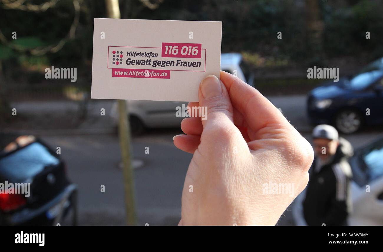Eine Frau hält eine Karte vom Beratungsangebot Das Hilfetelefon Gewalt ...