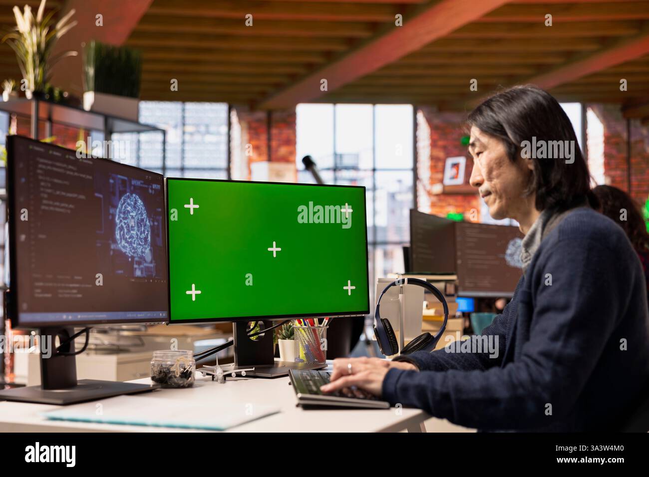 Software developer in pioneering technology startup using green screen computer to oversee ...