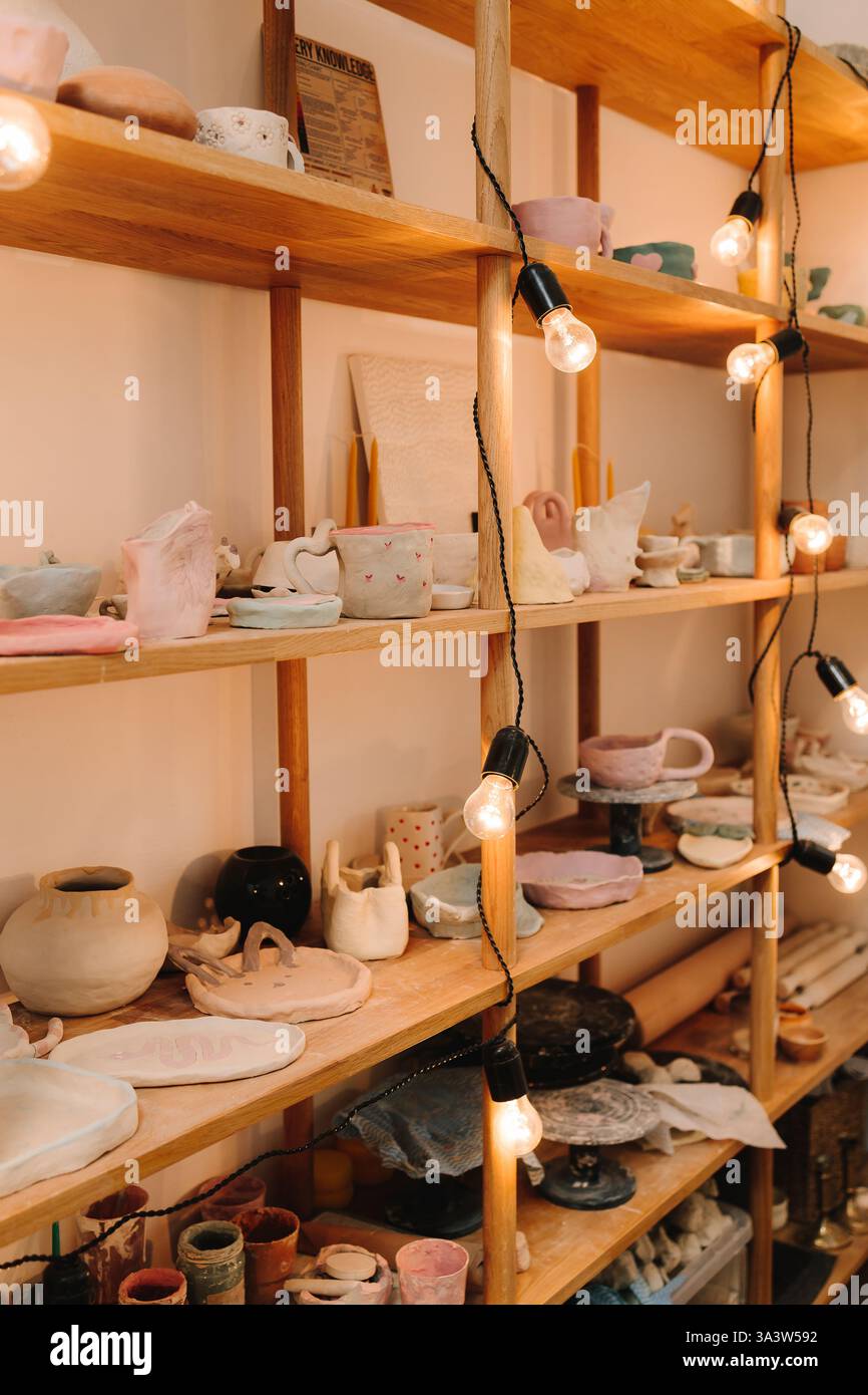 Shelf with handmade clay cups and plates in the pottery studio ...