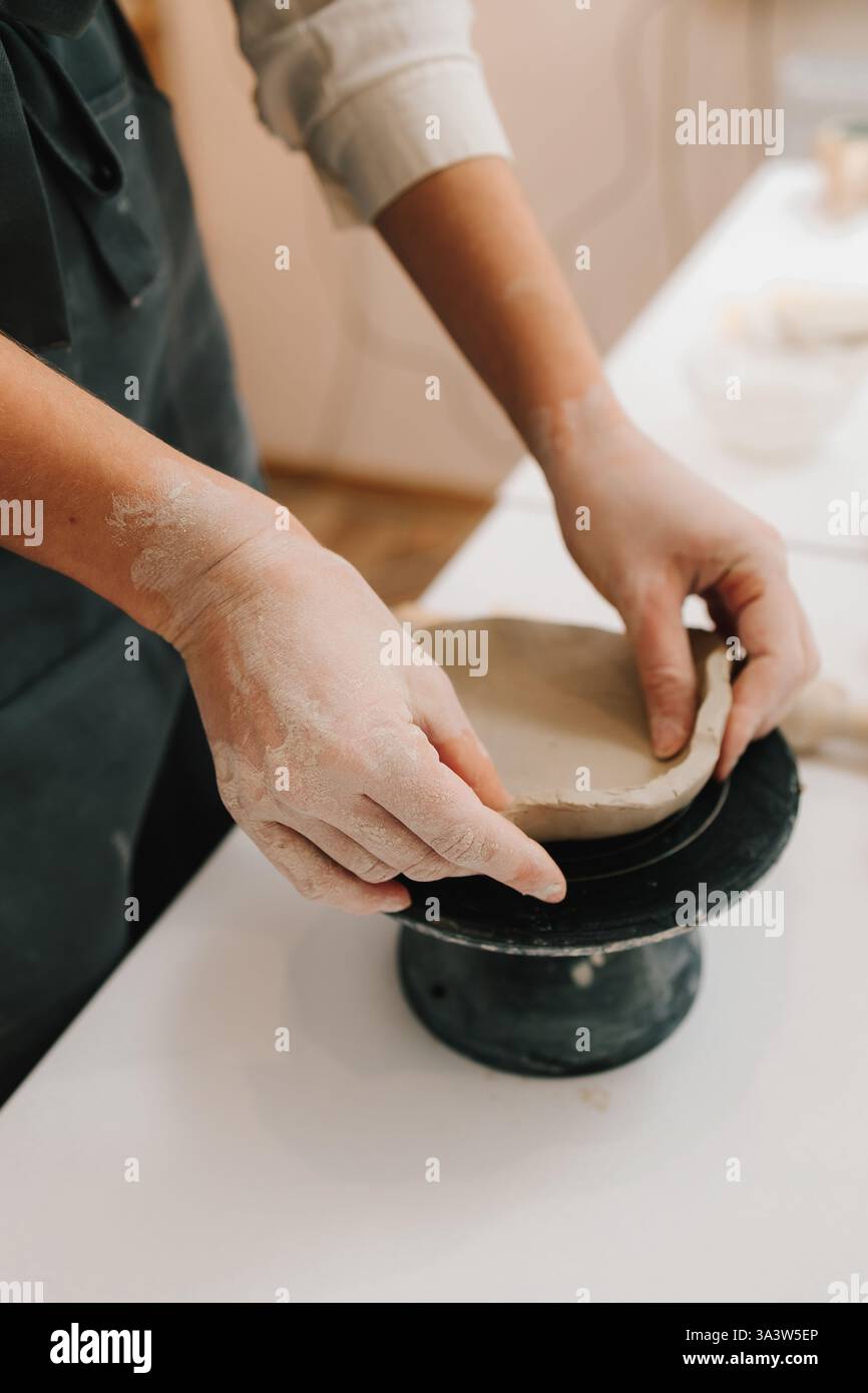Hands shaping clay into dish in the craft studio close-up. Artisan ...