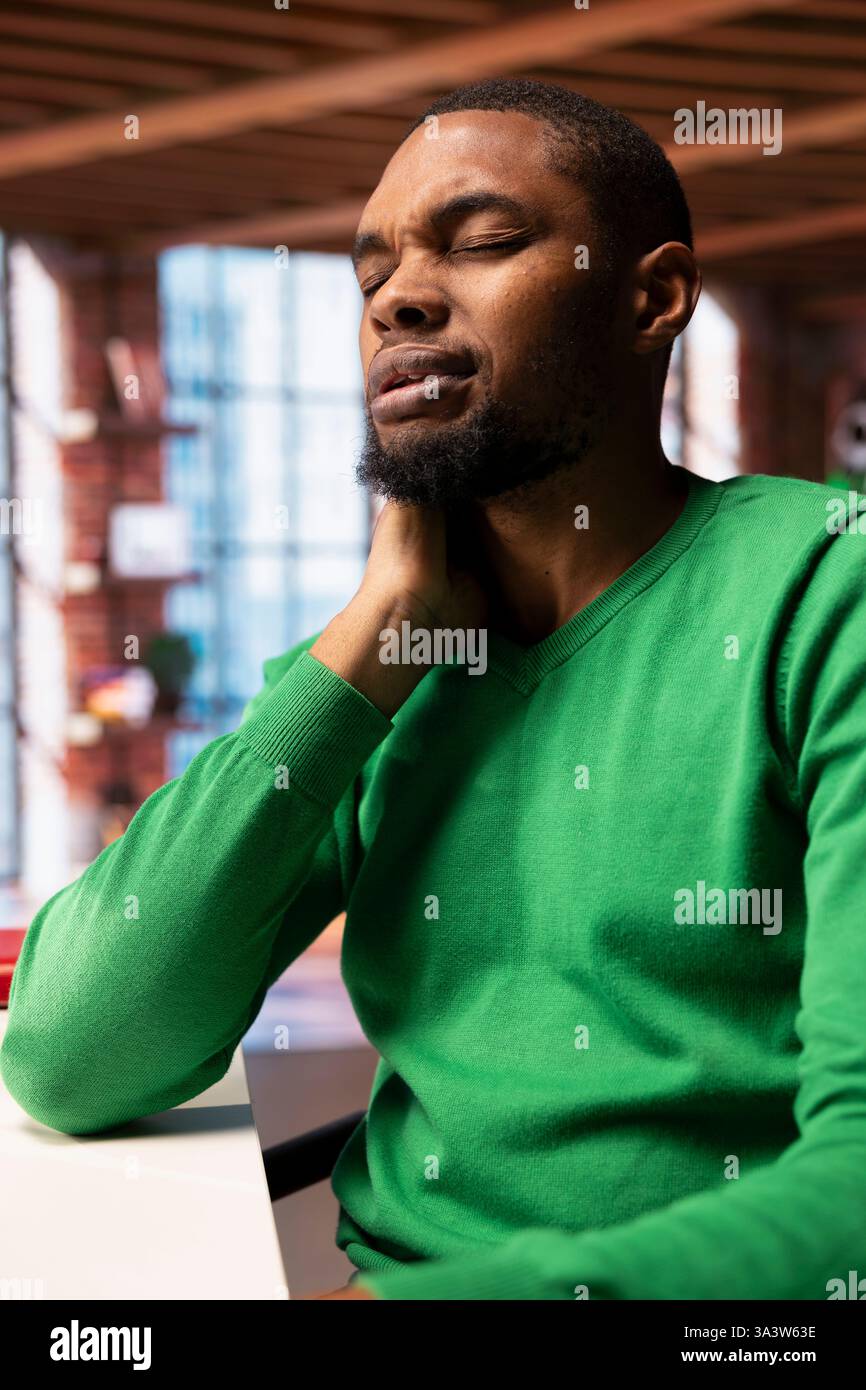 Teleworker in home office stretches neck, feeling fatigued while ...