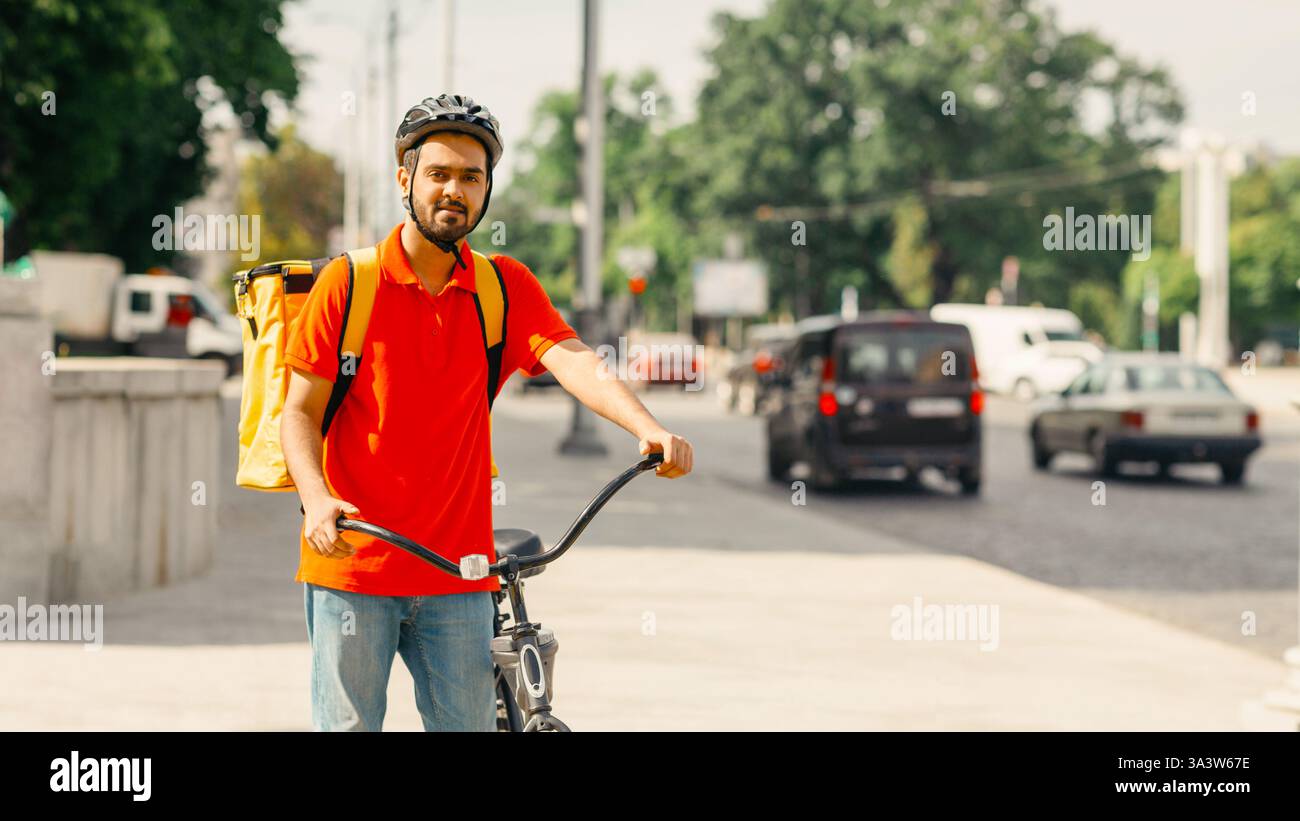 Goods delivery service. Friendly courier in helmet with big bag, stands ...