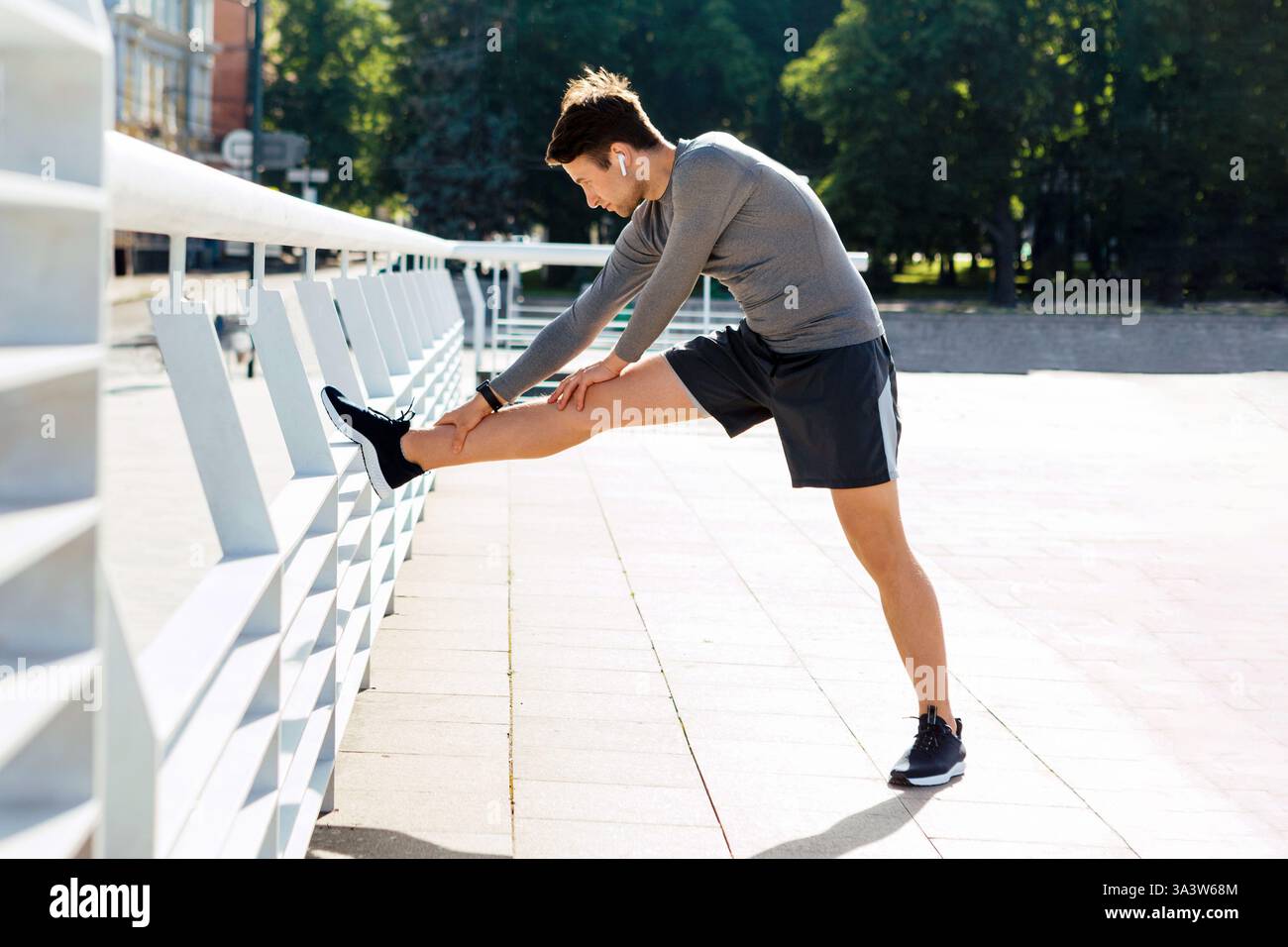 Stretching and end of workout. Muscular guy puts foot on railing and ...