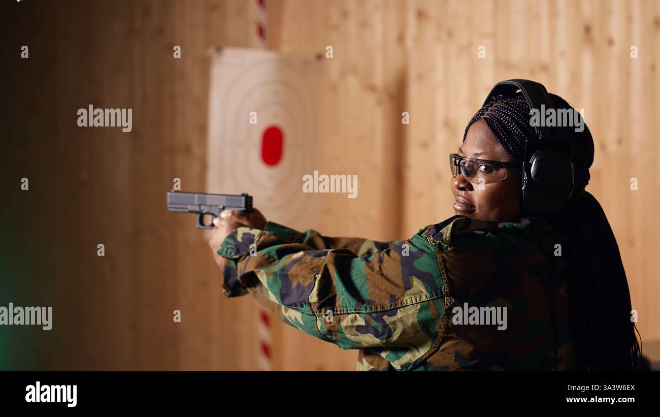 Portrait of smiling woman in firing range shooting with pistol, wearing ...