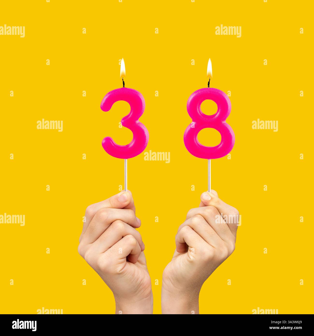 Hands holding birthday candles with number 38 - Yellow background Stock ...
