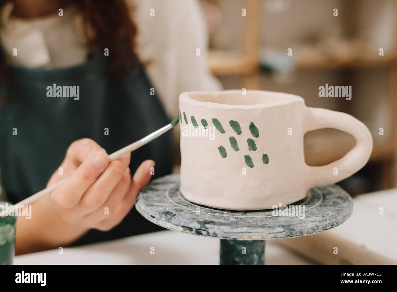 Artisan stamps decorative symbols on the dry clay of the cup. Process ...
