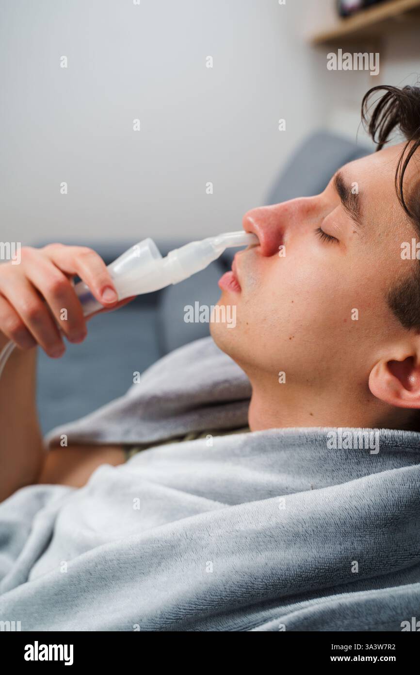 Doing nose inhalation with nebulizer at home. Young man with asthma ...