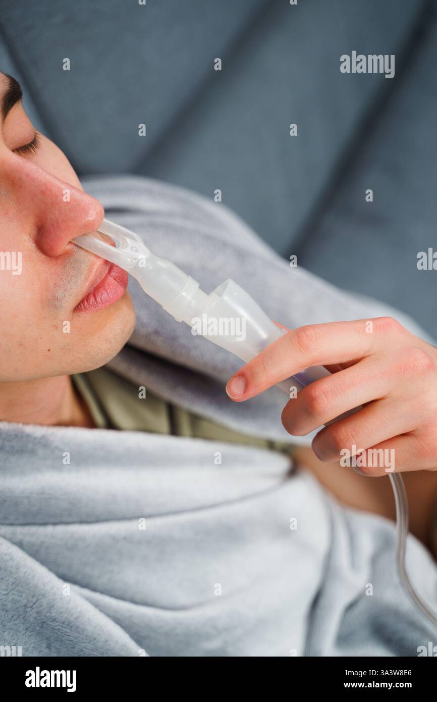 Doing nose inhalation with nebulizer at home. Young man with asthma ...
