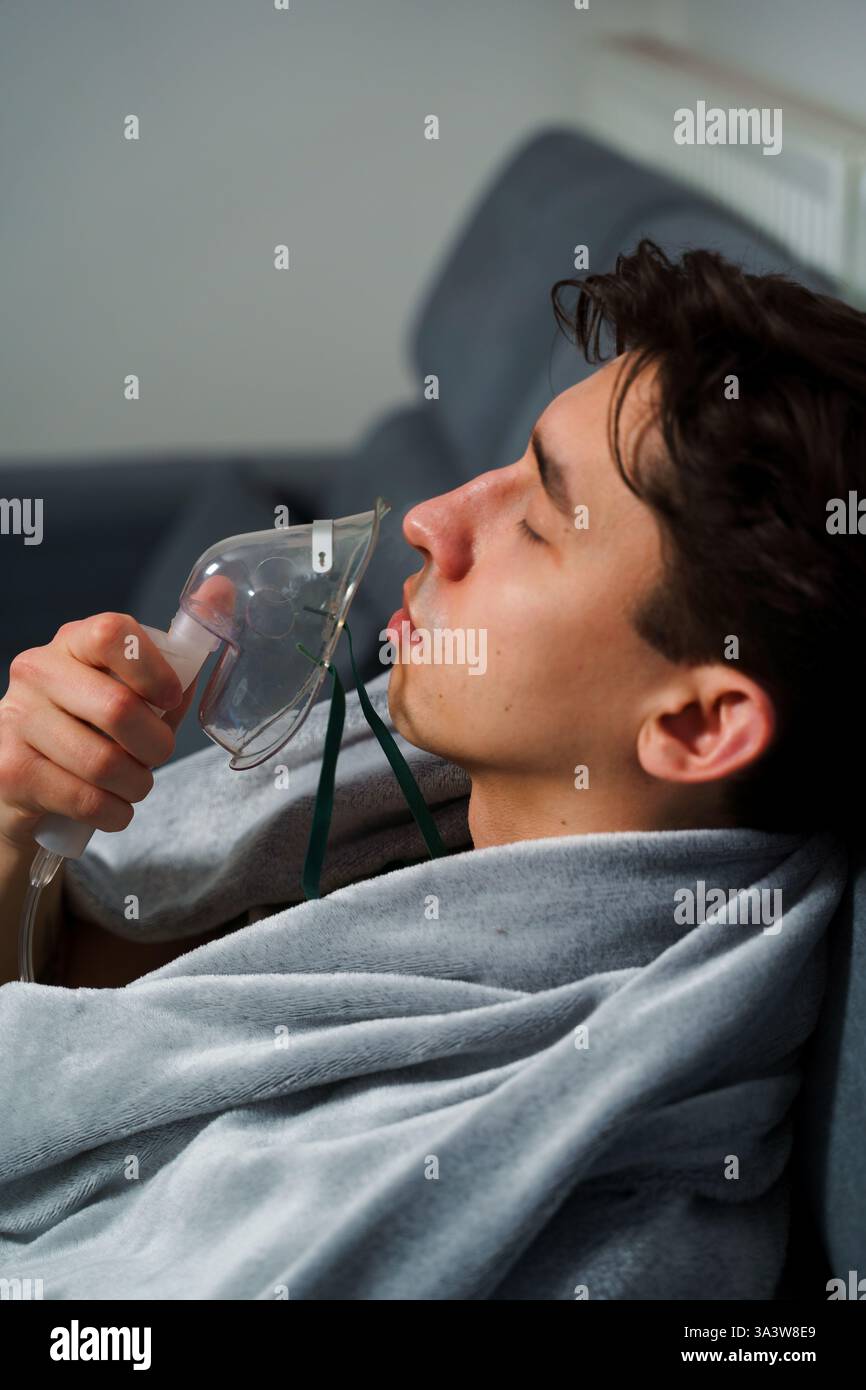 Man inhaling through oxygen mask for cough treatment. Using compressor ...