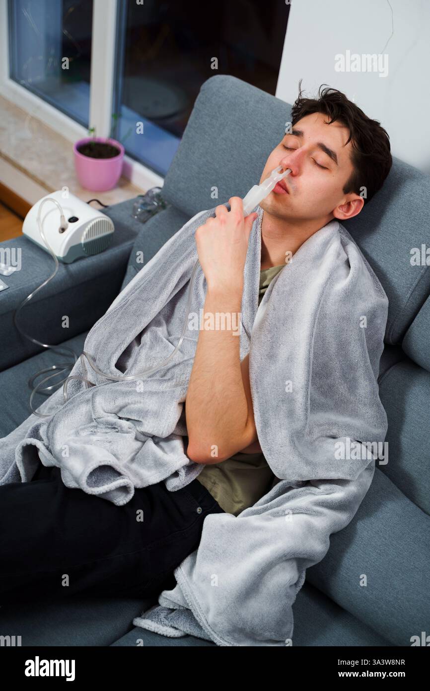 Doing nose inhalation with nebulizer at home. Young man with asthma ...