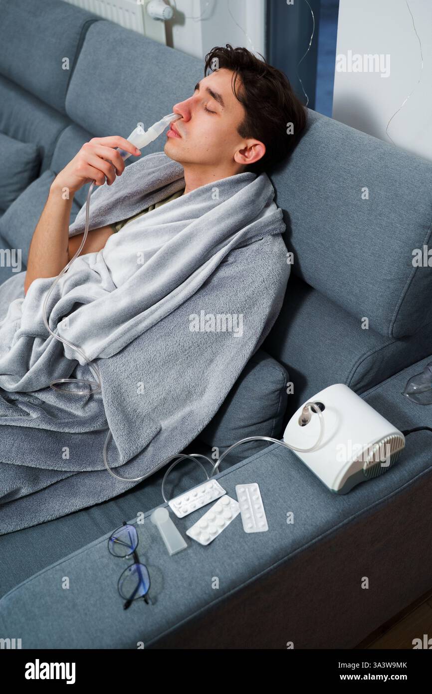 Doing nose inhalation with nebulizer at home. Young man with asthma ...