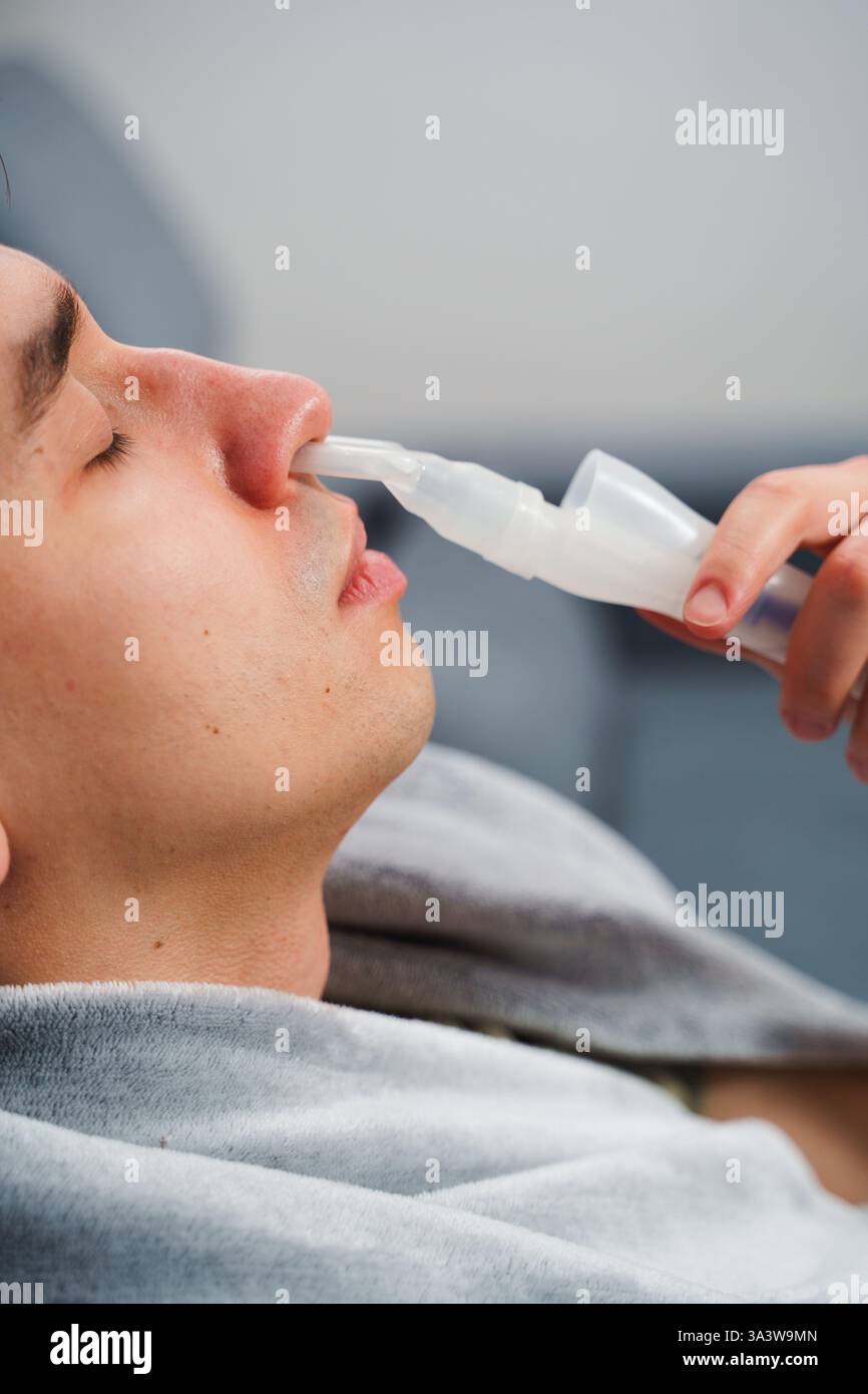Doing nose inhalation with nebulizer at home. Young man with asthma ...
