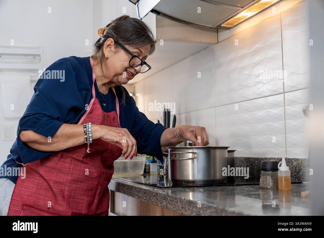 Happy retired woman adding spices to pot on stove Stock Photo - Alamy