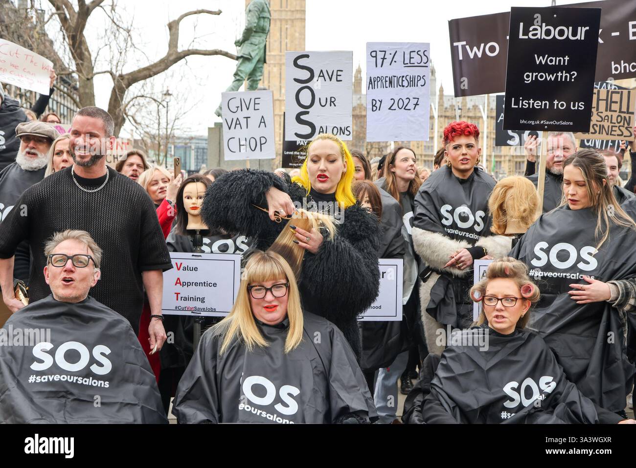Beauty sector staff members wearing black gowns hold placards during a ...