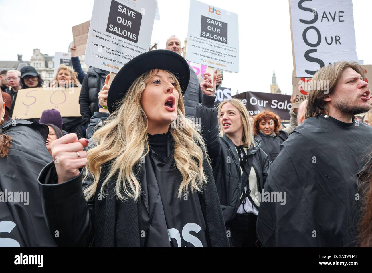 Beauty sector staff members wearing black gowns hold placards during a ...