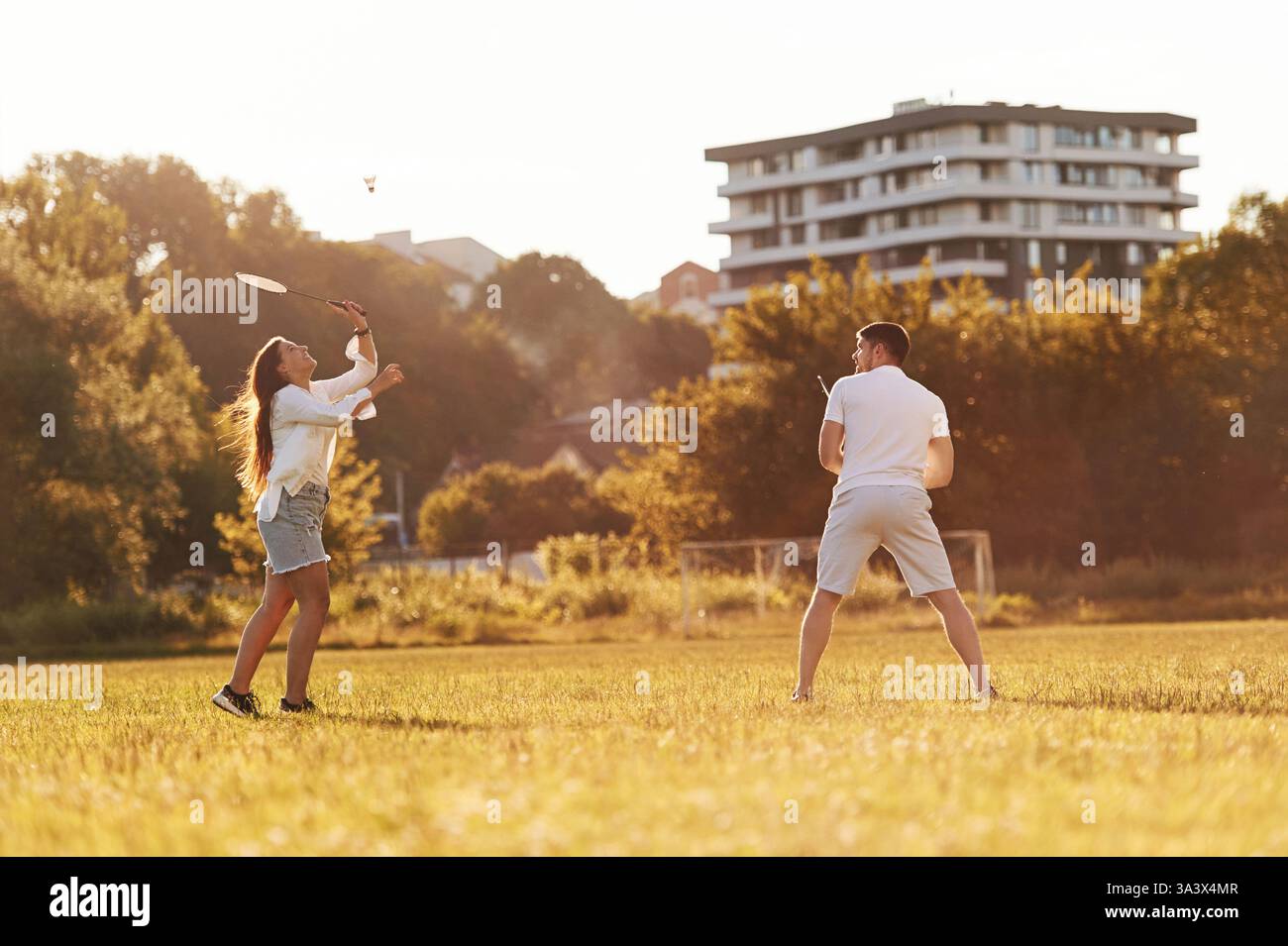Side view. Man with woman are playing badminton on the field Stock ...