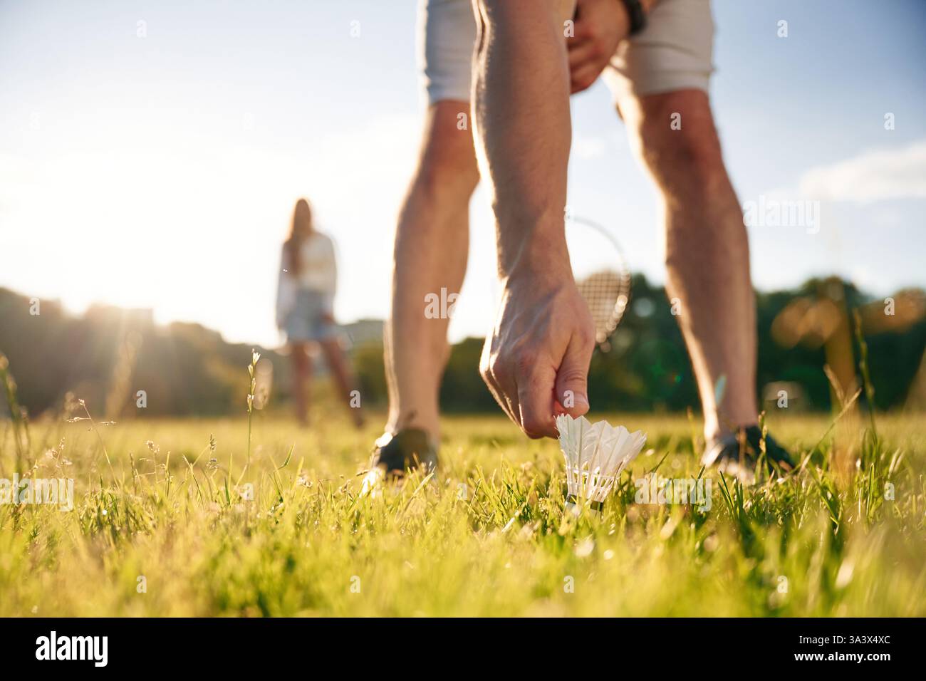 Guy is picking up the shuttlecock. Man with woman are playing badminton ...