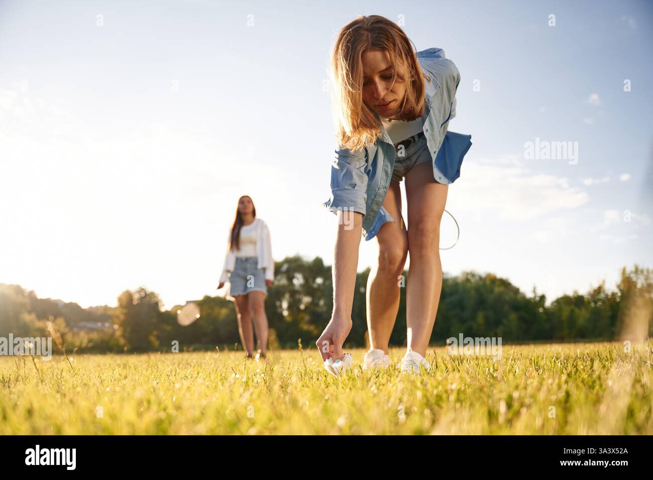 Picking up the fallen shuttlecock. Two women are having fun, with ...