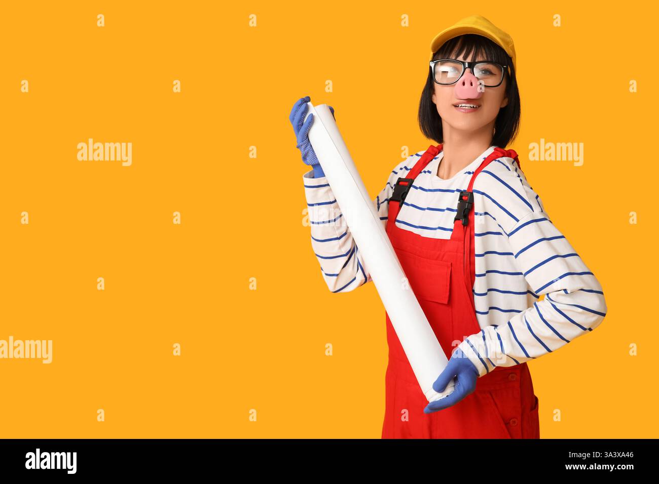 Funny young female decorator with house plan on orange background. Fool ...