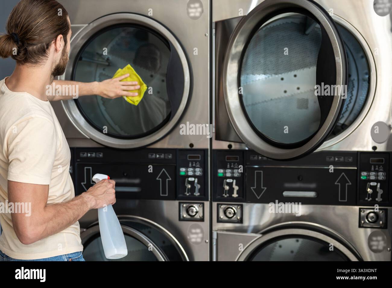 Male cleaning washing machine and dryer in laundromat Stock Photo - Alamy