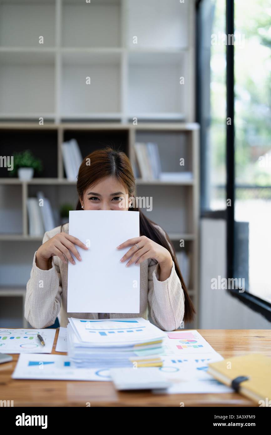 Young woman in beige long-sleeved shirt playfully hiding her face with ...