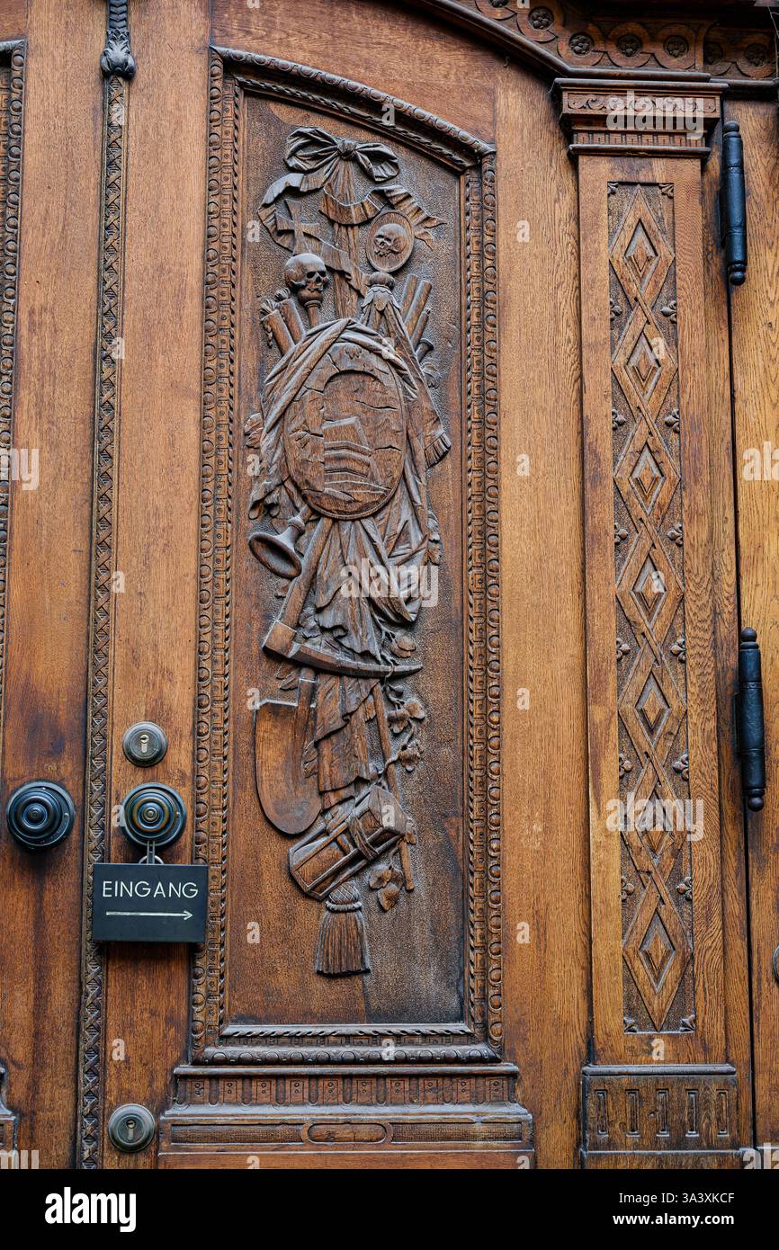 Entrance sign in German on an old and richly decorated wooden door ...