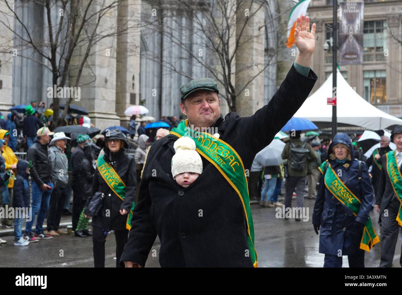 New York, USA.17th March 2025. A child is carried in a marcher's coat ...