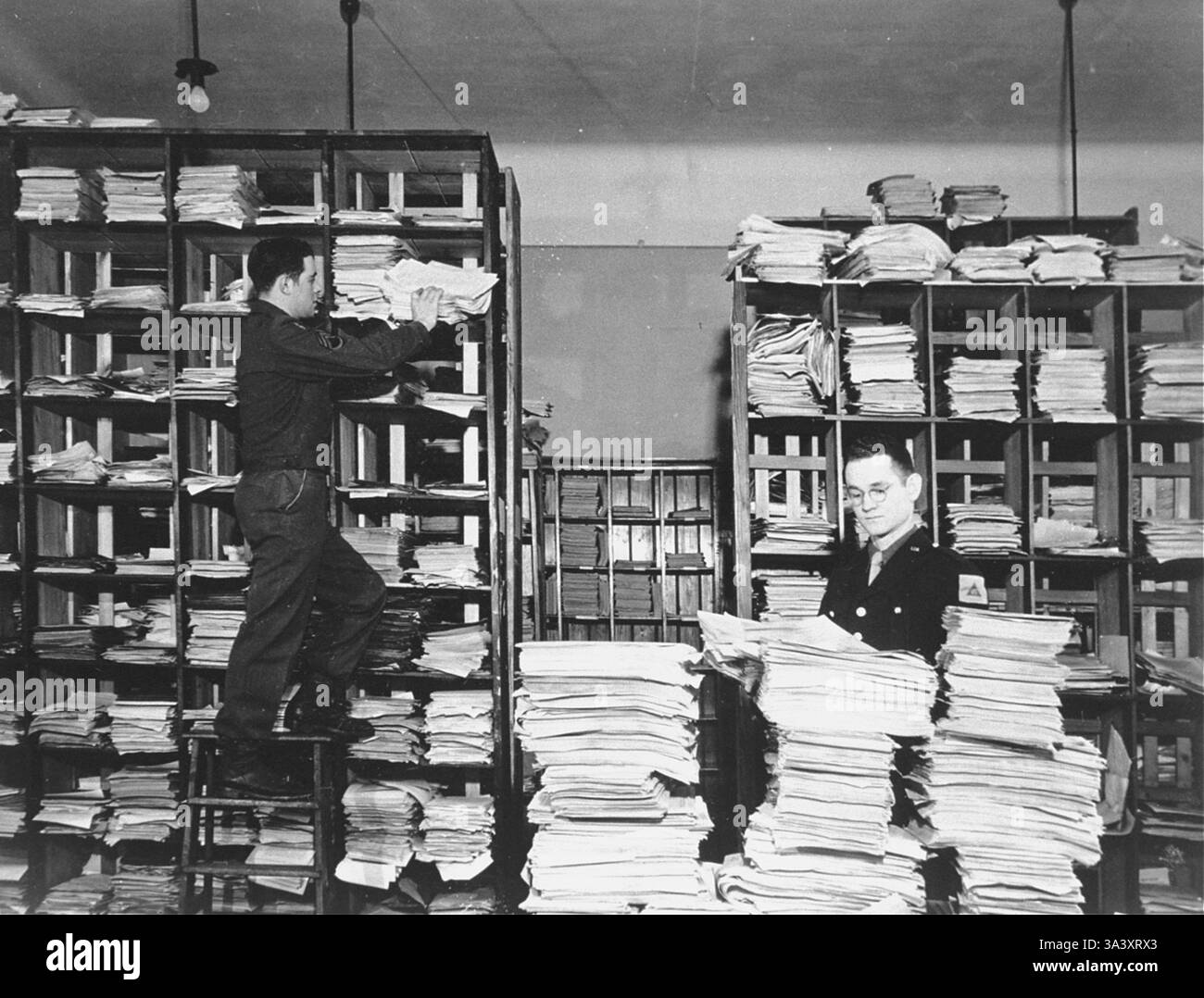 American army staffers organize stacks of German documents that were ...