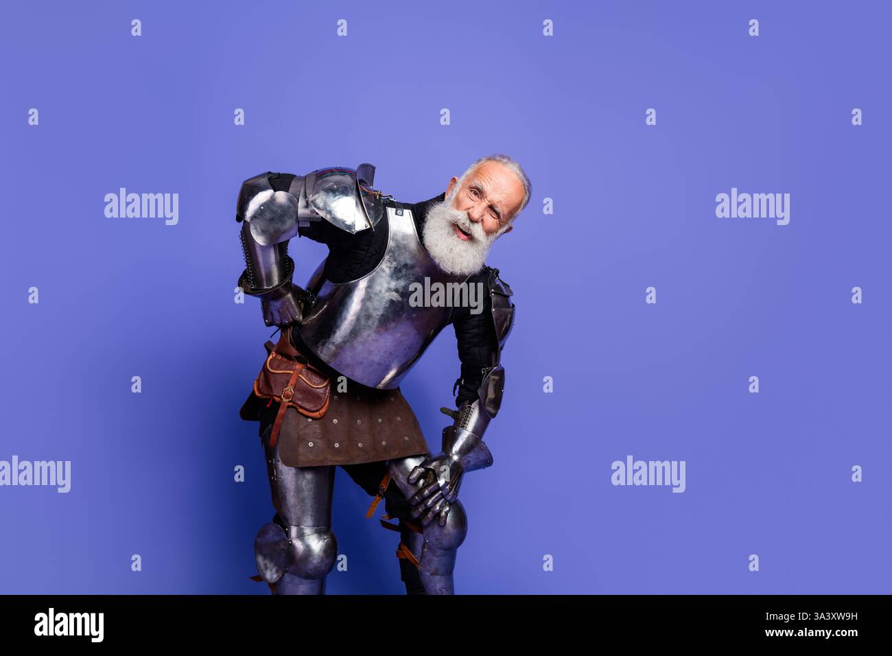Elderly knight with a beard in full armor posing against a violet ...