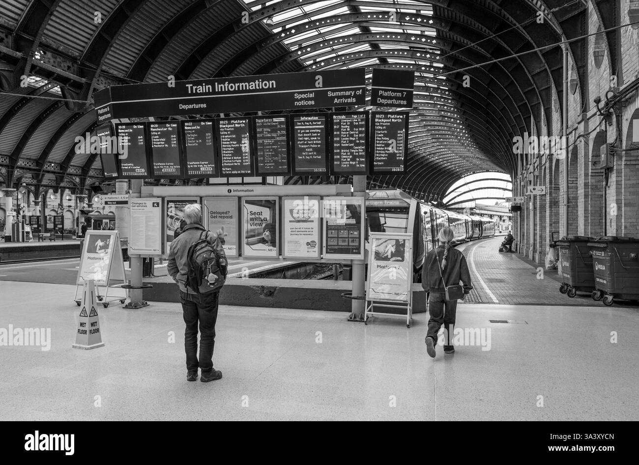 Passengers viewing the train timetable on a large electronic display at ...