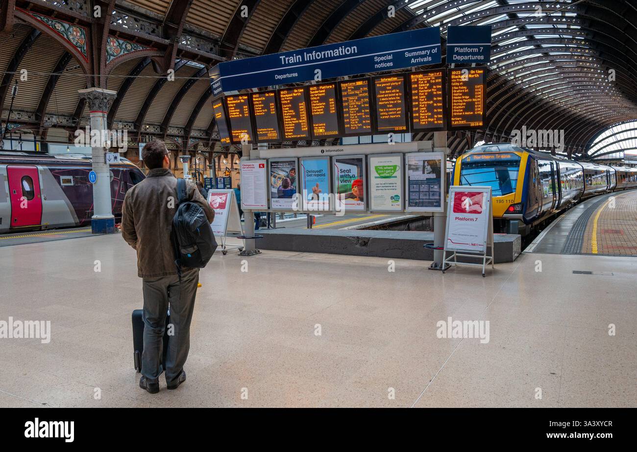 Passengers viewing the train timetable on a large electronic display at ...