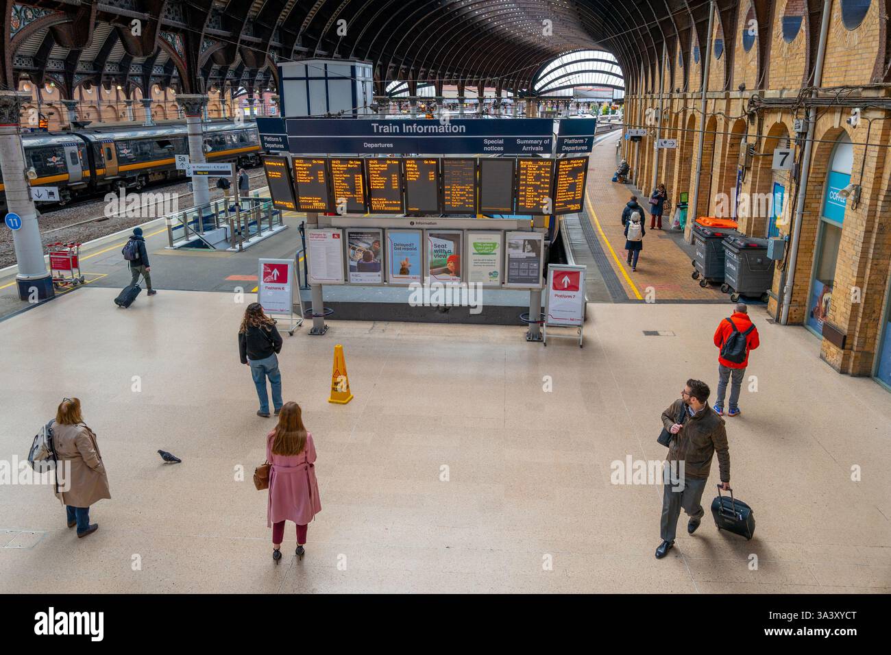 Passengers viewing the train timetable on a large electronic display at ...