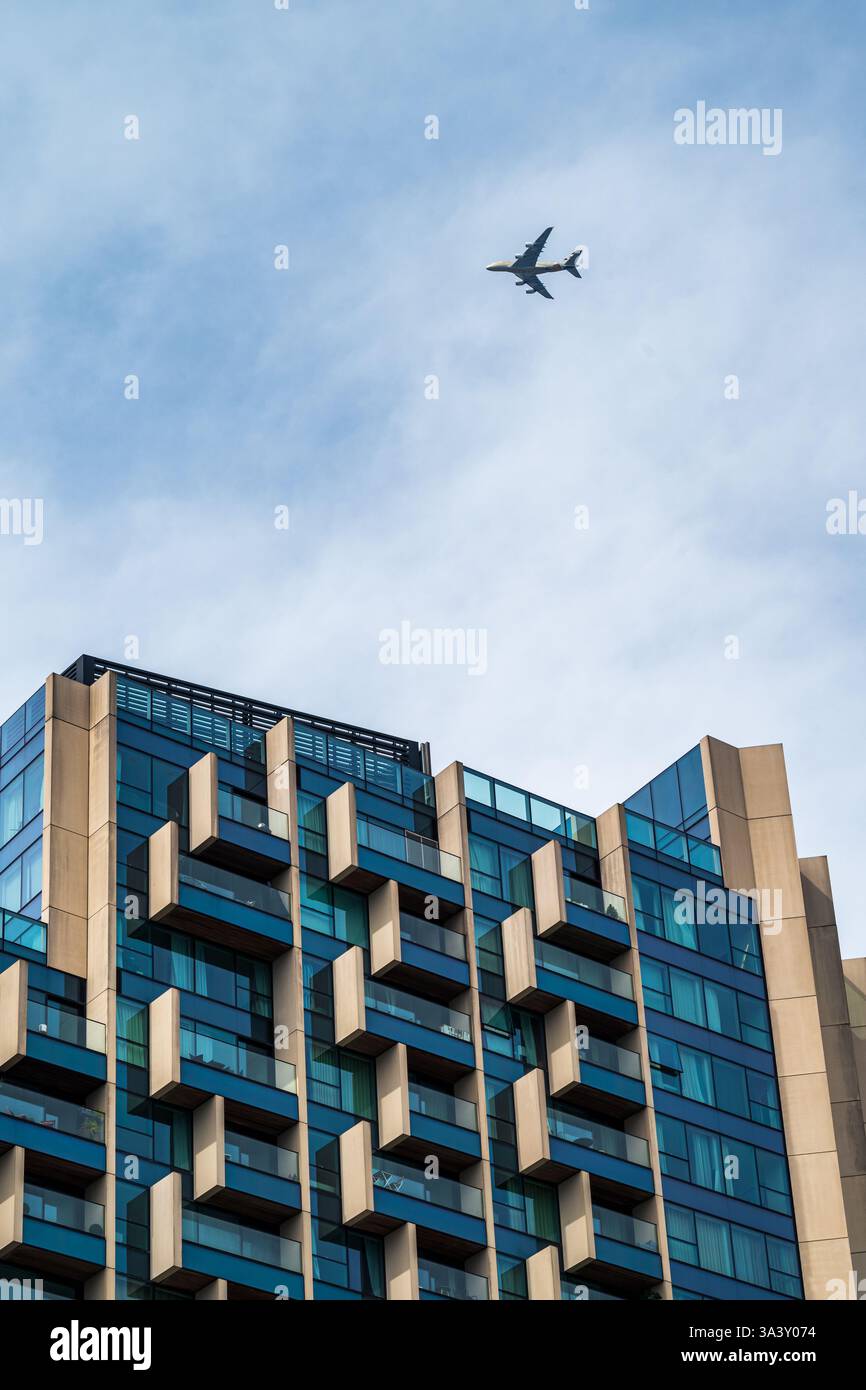 The top of high-end modern apartments and a commercial airplane passing ...