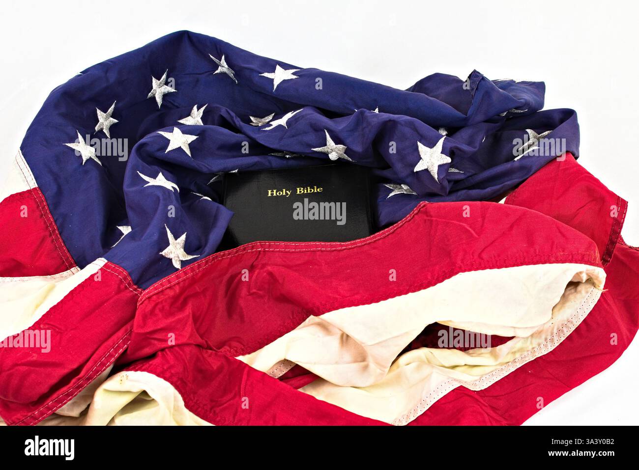 An unfolded US flag wrapped around a Bible on a white background Stock ...