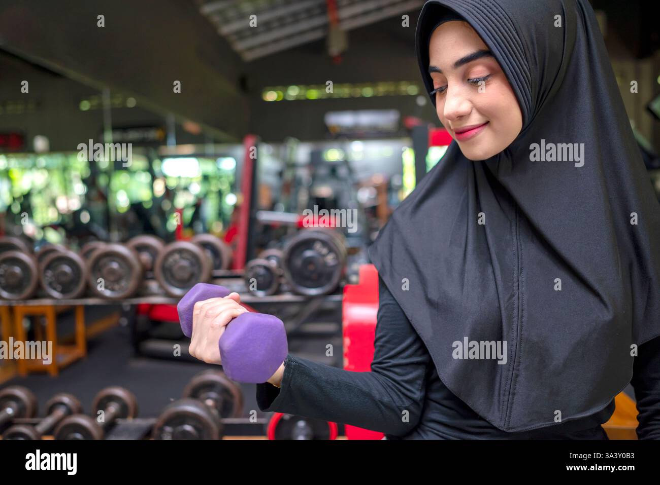 Arab middle eastern muslim woman working out while lifting a dumbbell ...