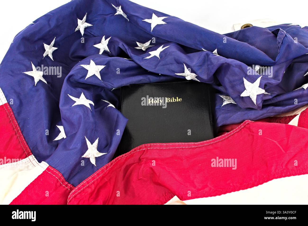 An unfolded US flag draped across a Bible on a white background Stock ...