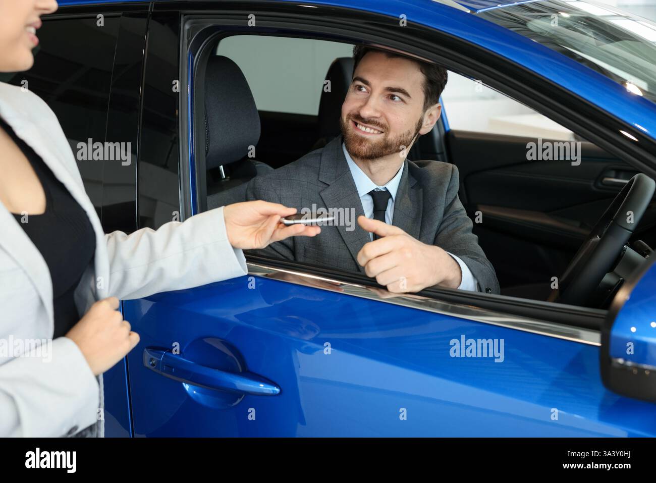 Saleswoman giving key to happy client inside new car in salon Stock ...