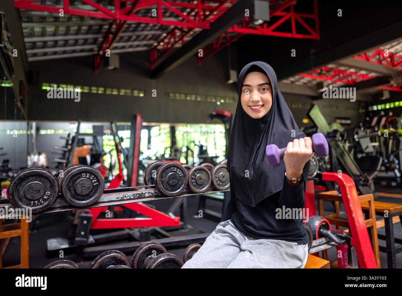Arab middle eastern muslim woman working out while lifting a dumbbell ...