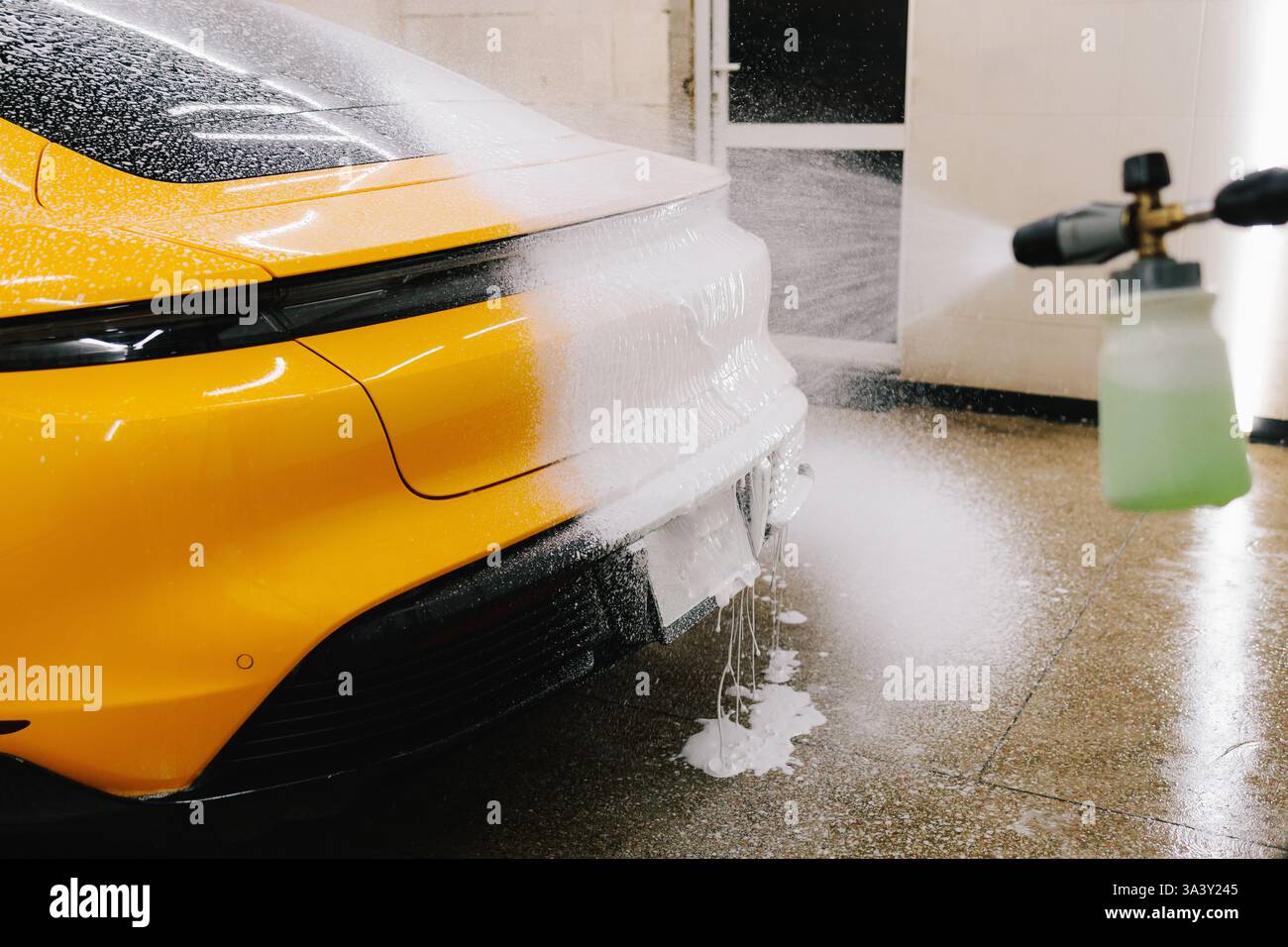 Worker sprays soap solution with pressure from water jet for detailing ...