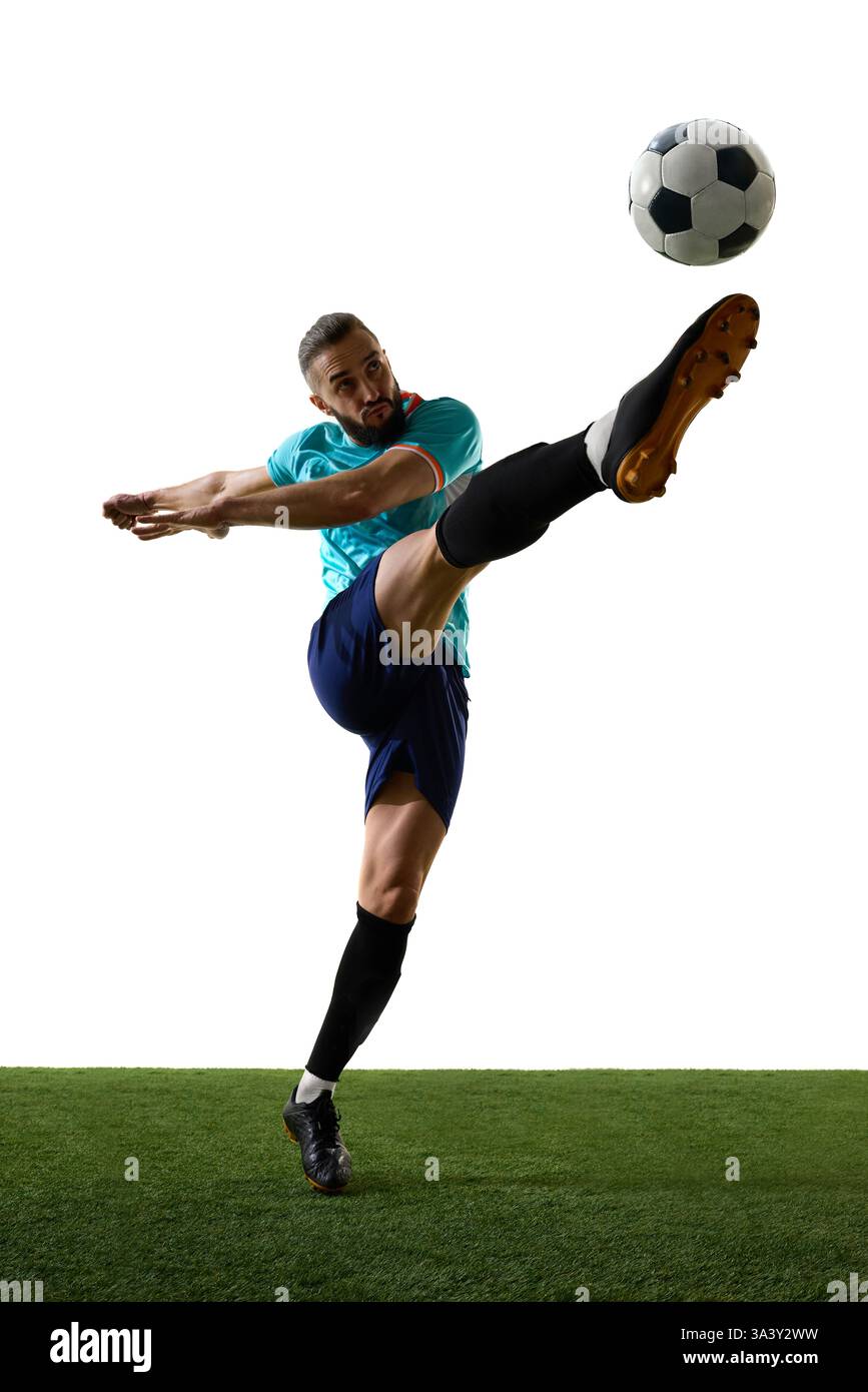 Agile football player in blue sportswear executing powerful high kick, sending ball soaring ...