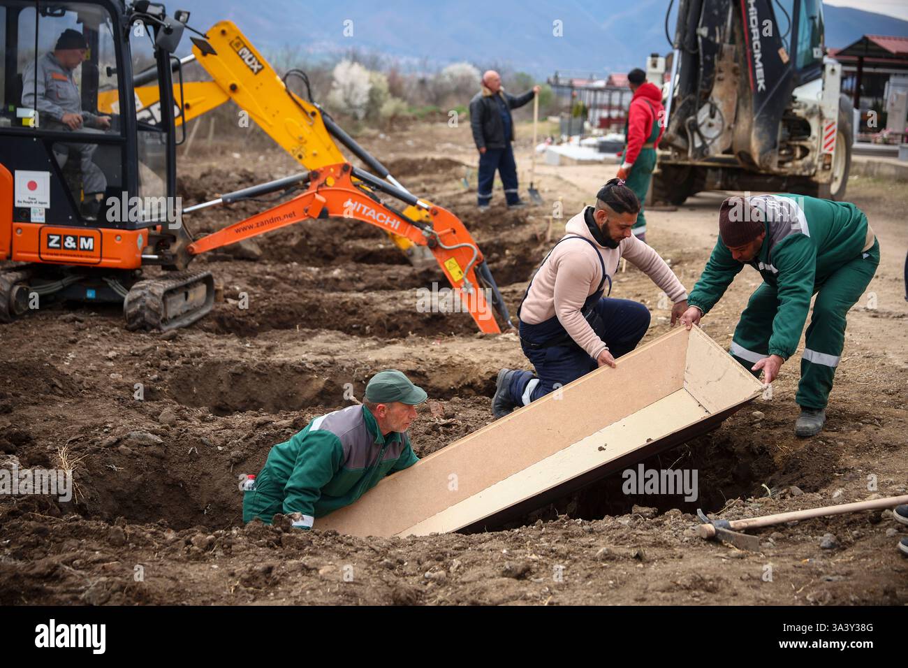 Municipal workers use an empty coffin to measure the graves they are ...