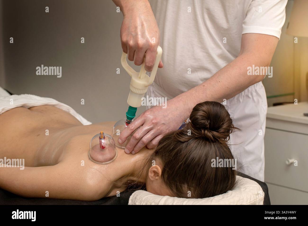 A therapeutic session featuring cupping therapy on a woman's back in a relaxing spa setting ...