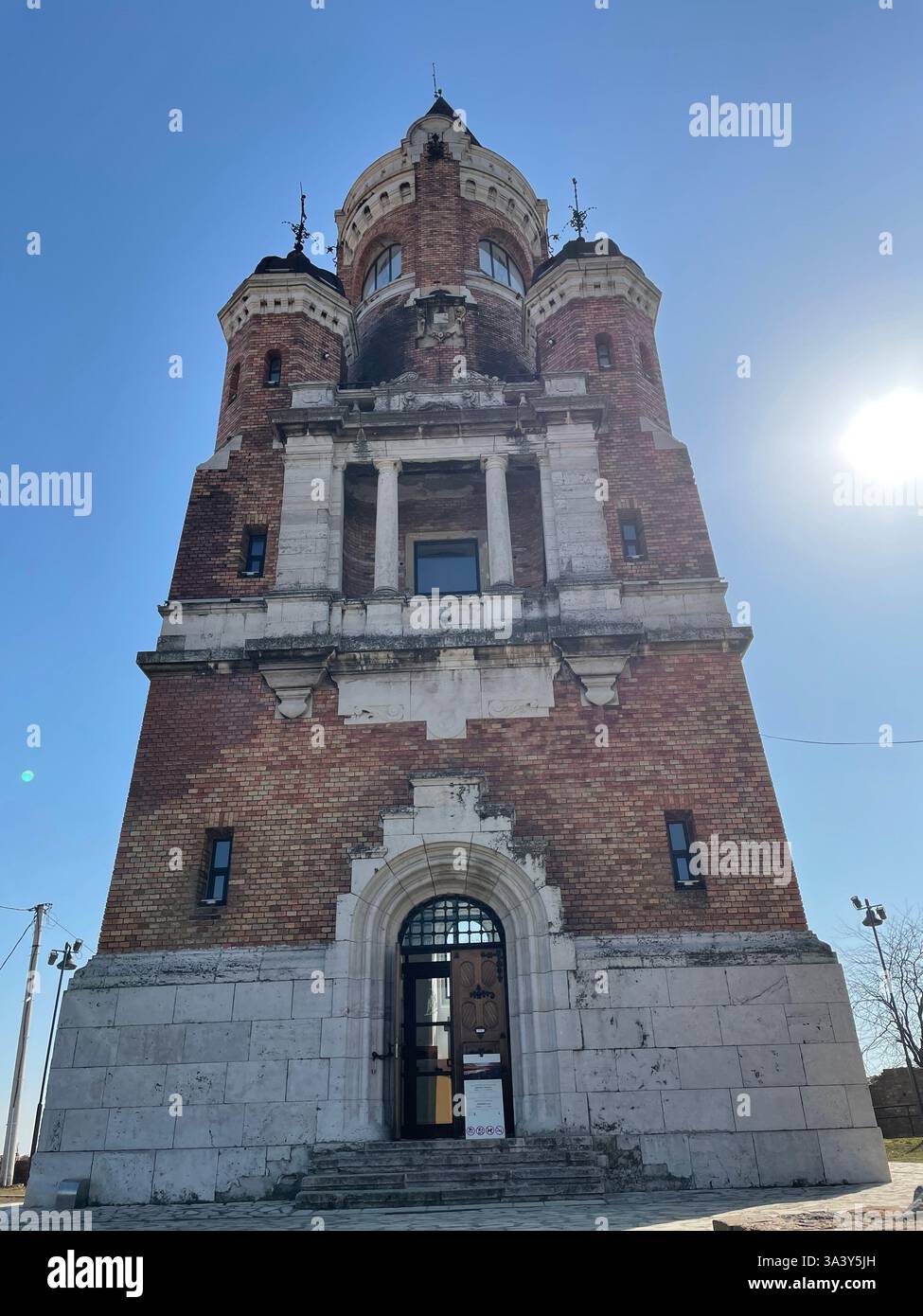 An architectural, medieval red-brick tower with white stone accents ...