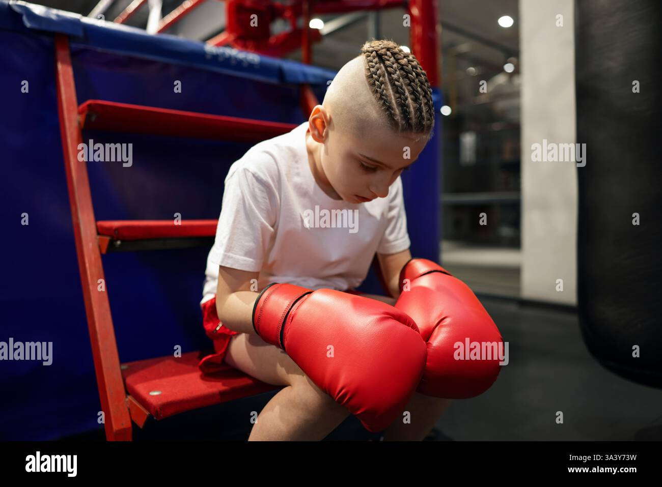 Sad boy in protective gloves sitting near boxing ring Stock Photo - Alamy