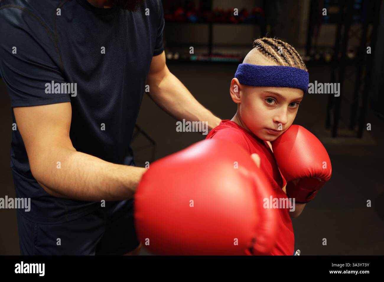 Boy in protective gloves with his boxing coach at training center Stock ...
